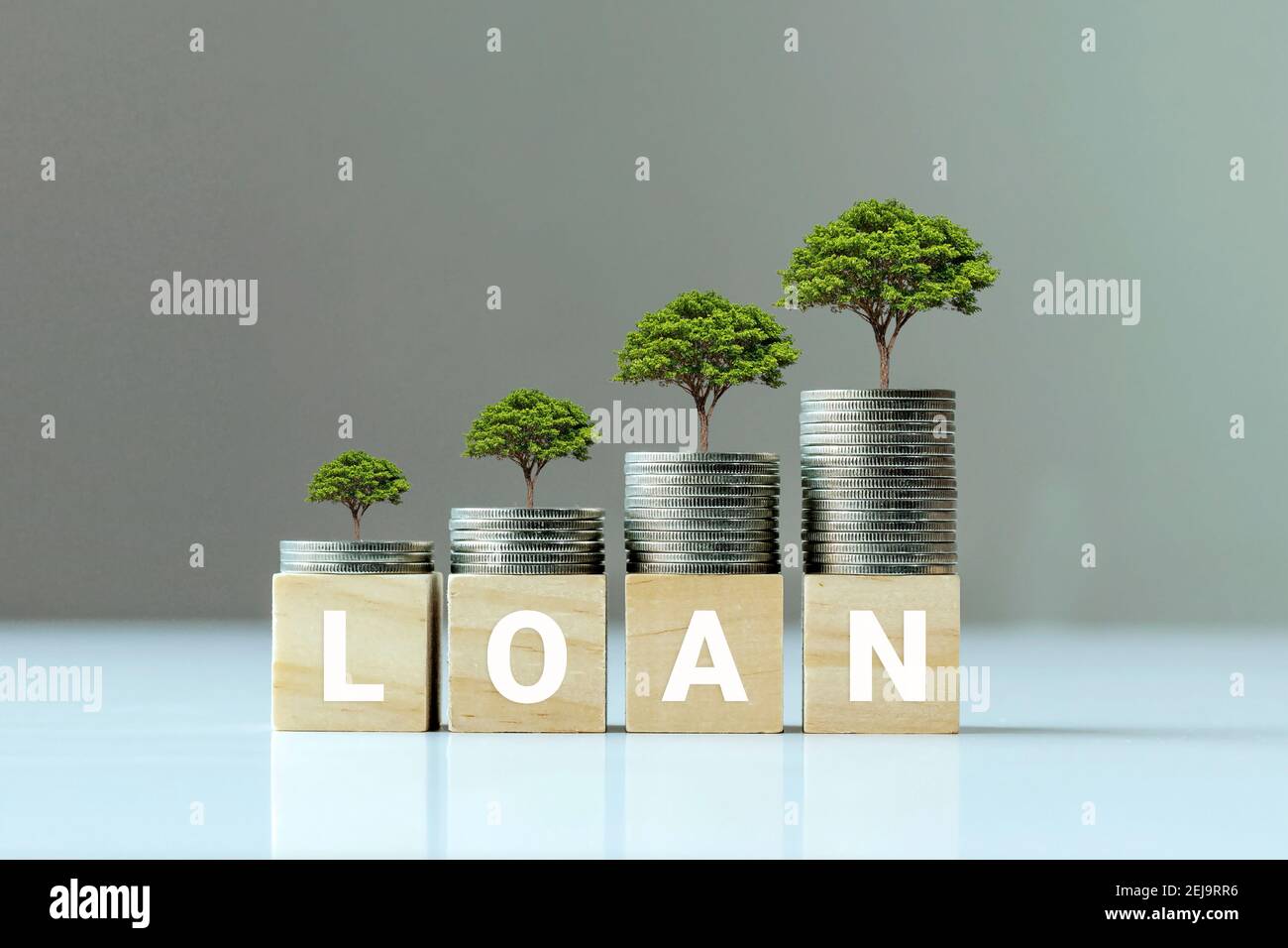 Growing plant on coin pile and wood block with loan text, finance ideas ...