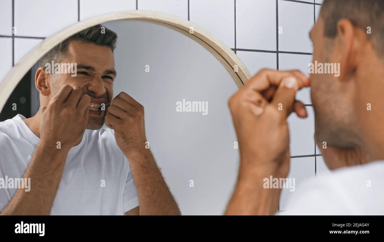 young man cleaning teeth with dental floss in bathroom Stock Photo - Alamy
