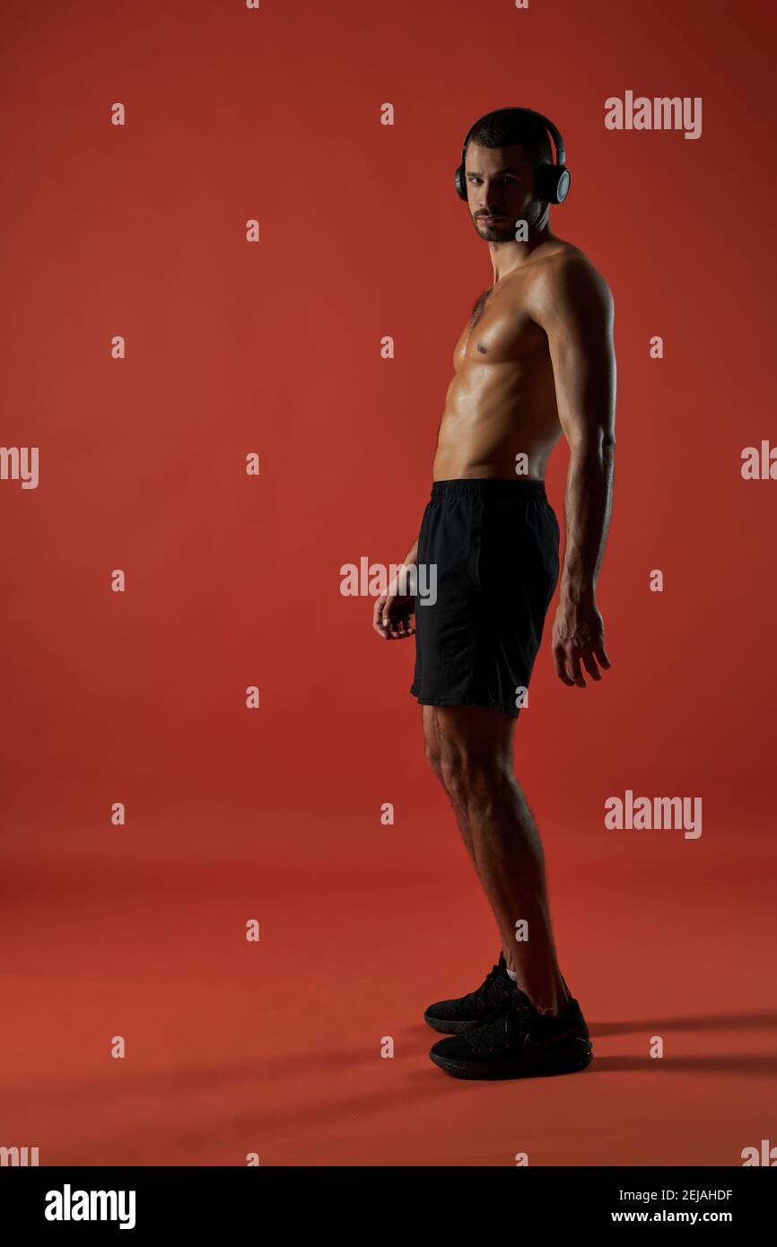 Full length side view portrait of tired Caucasian athlete in black ...