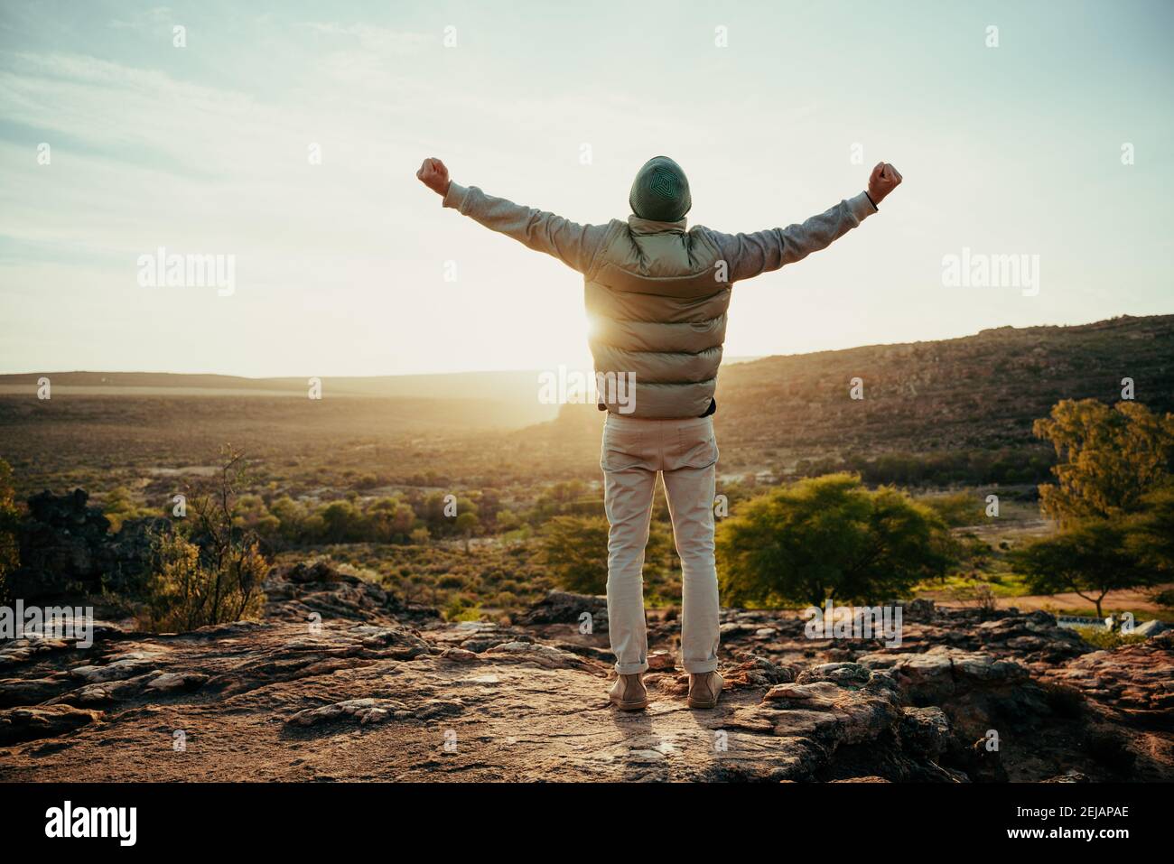 Caucasian male free spirit embracing sunset with arms wide while ...