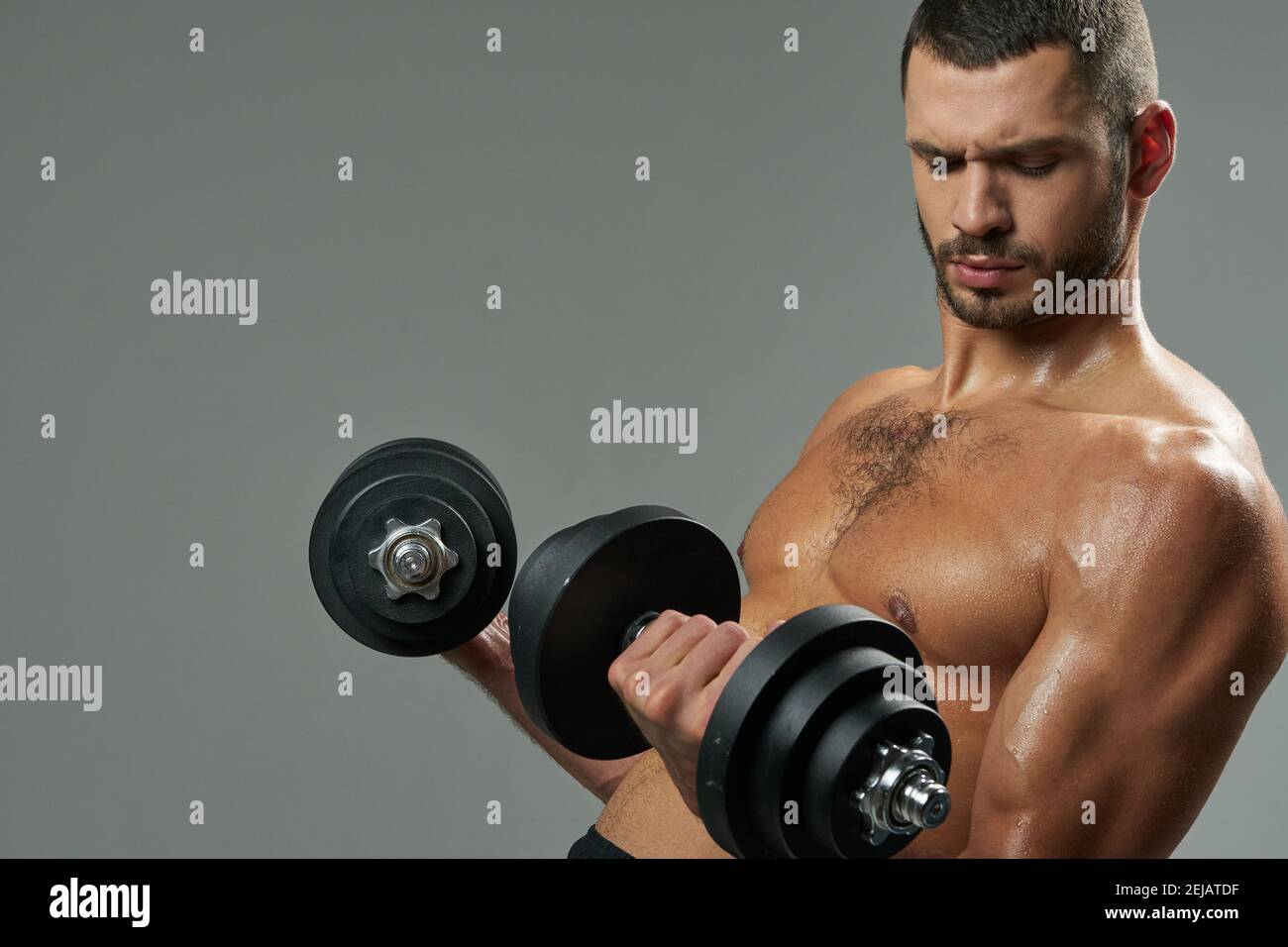 Waist up side view portrait of handsome strong bodybuilder developing ...
