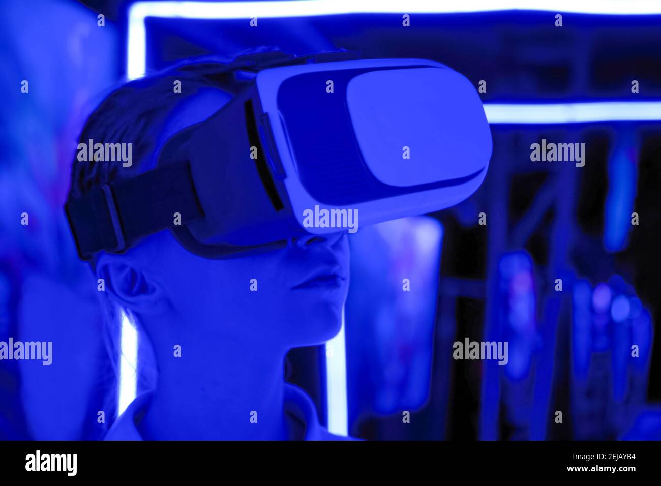 Young woman using virtual reality headset at dark interactive VR ...