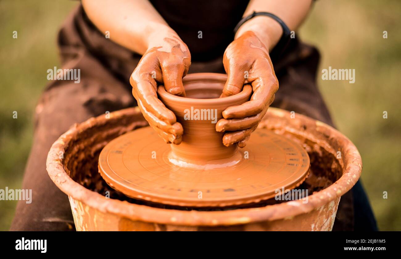 Hands of potter make ceramic jar on pottery wheel outdoor, selective ...