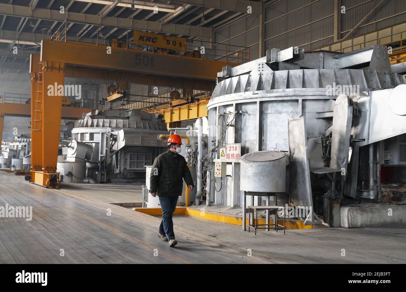 A Chinese worker walks past furnaces at a recycled aluminium ...