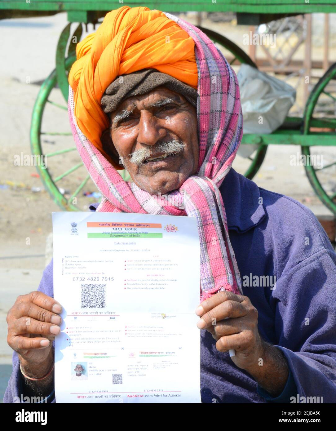 An elderly rajasthani man in turban shows his identity card at a ...