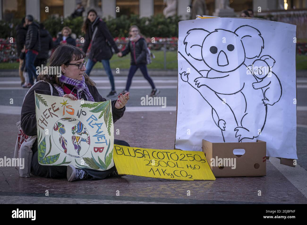 A climate activist holds a placard while sitting on the ground during ...