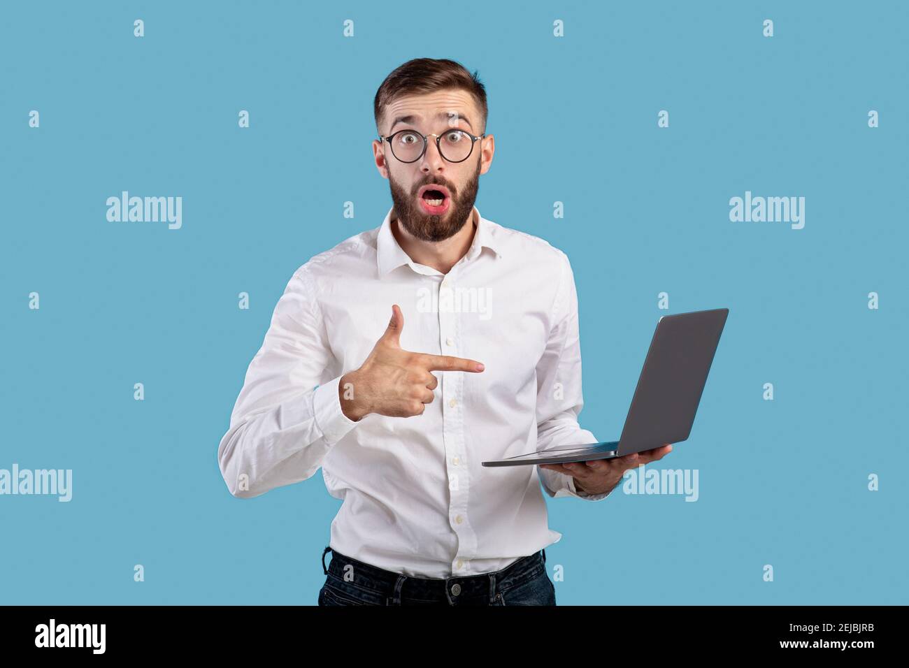 Shocked young man pointing at laptop computer with open mouth ...