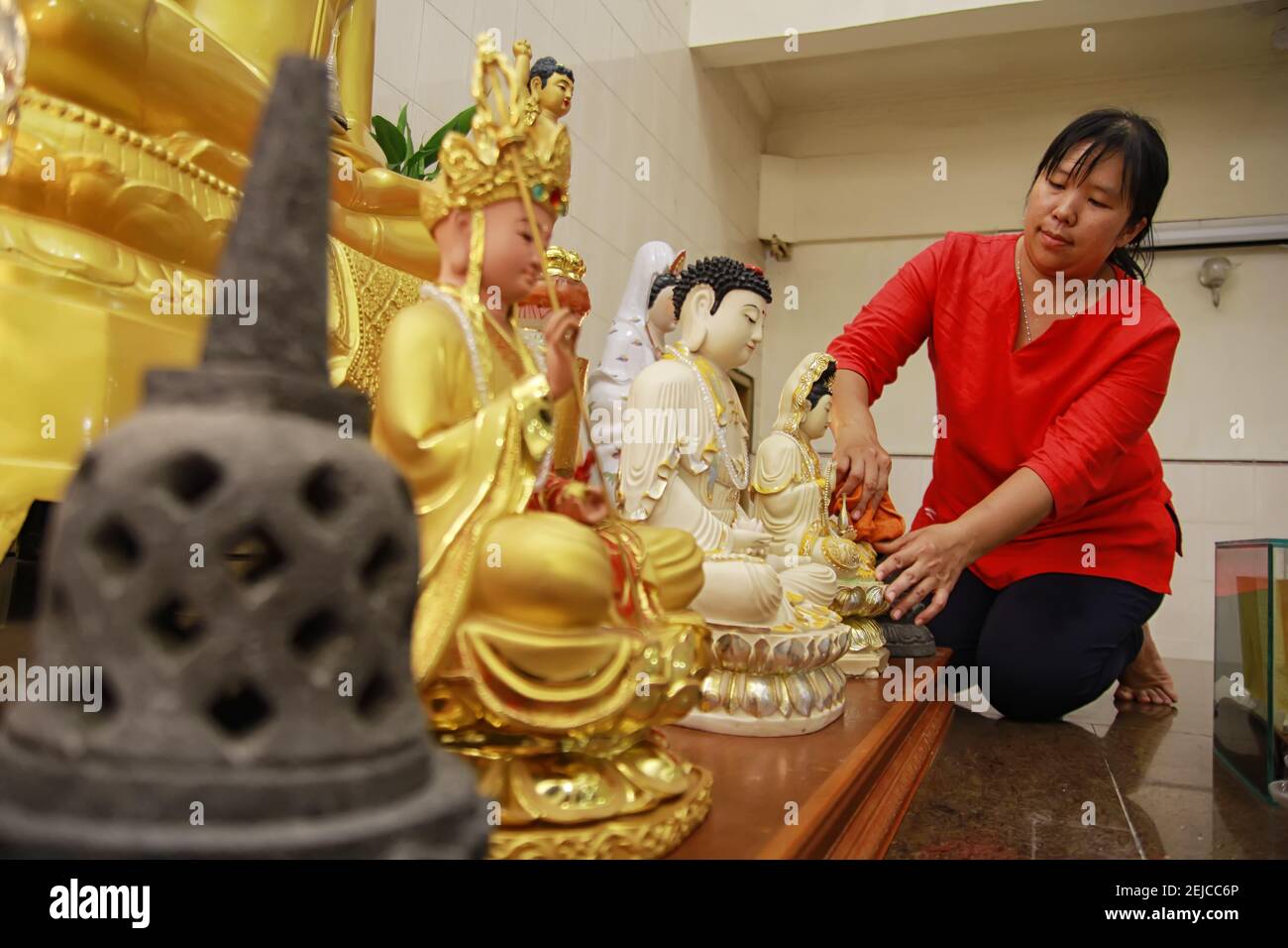 A woman cleans a buddhas statue during the celebration at Sakyamuni ...