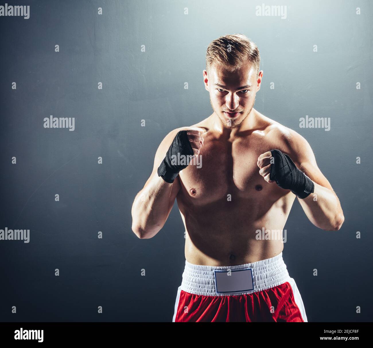 Boxer standing in fighting position on dark background. Professional ...
