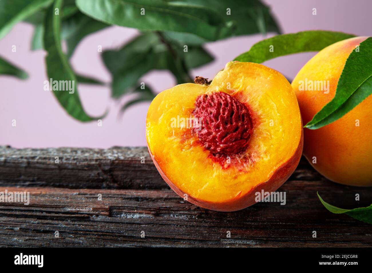 Peach in halves with bone. Peaches with leaves on wooden board. Ripe ...