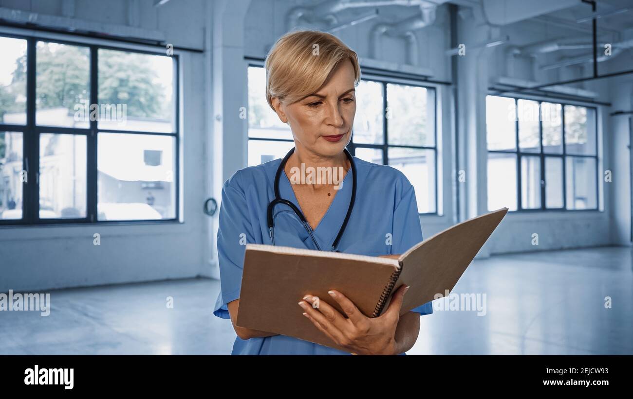 Mature doctor holding notebook in hospital Stock Photo - Alamy