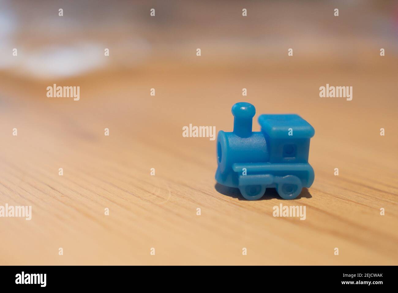 A small plastic blue toy train close up image on top of a wooden ...