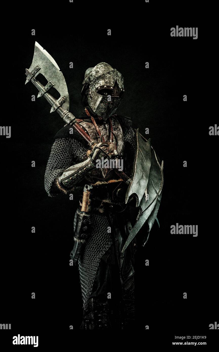 Medieval fighter in armor, carrying a shield and an ax on his shoulder ...