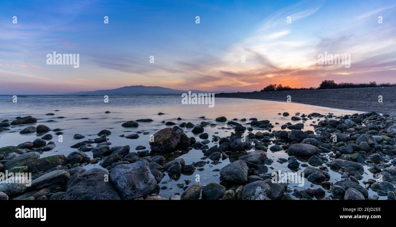 A colorful sunset on the Mediterranean Sea in Almeria with rocks and ...