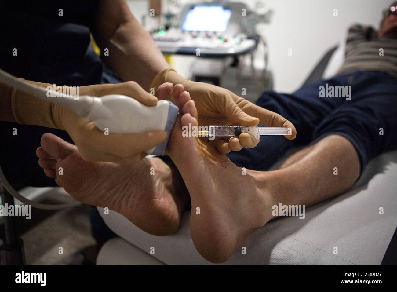 Radiologist performing an infiltration, under ultrasound, to a patient ...