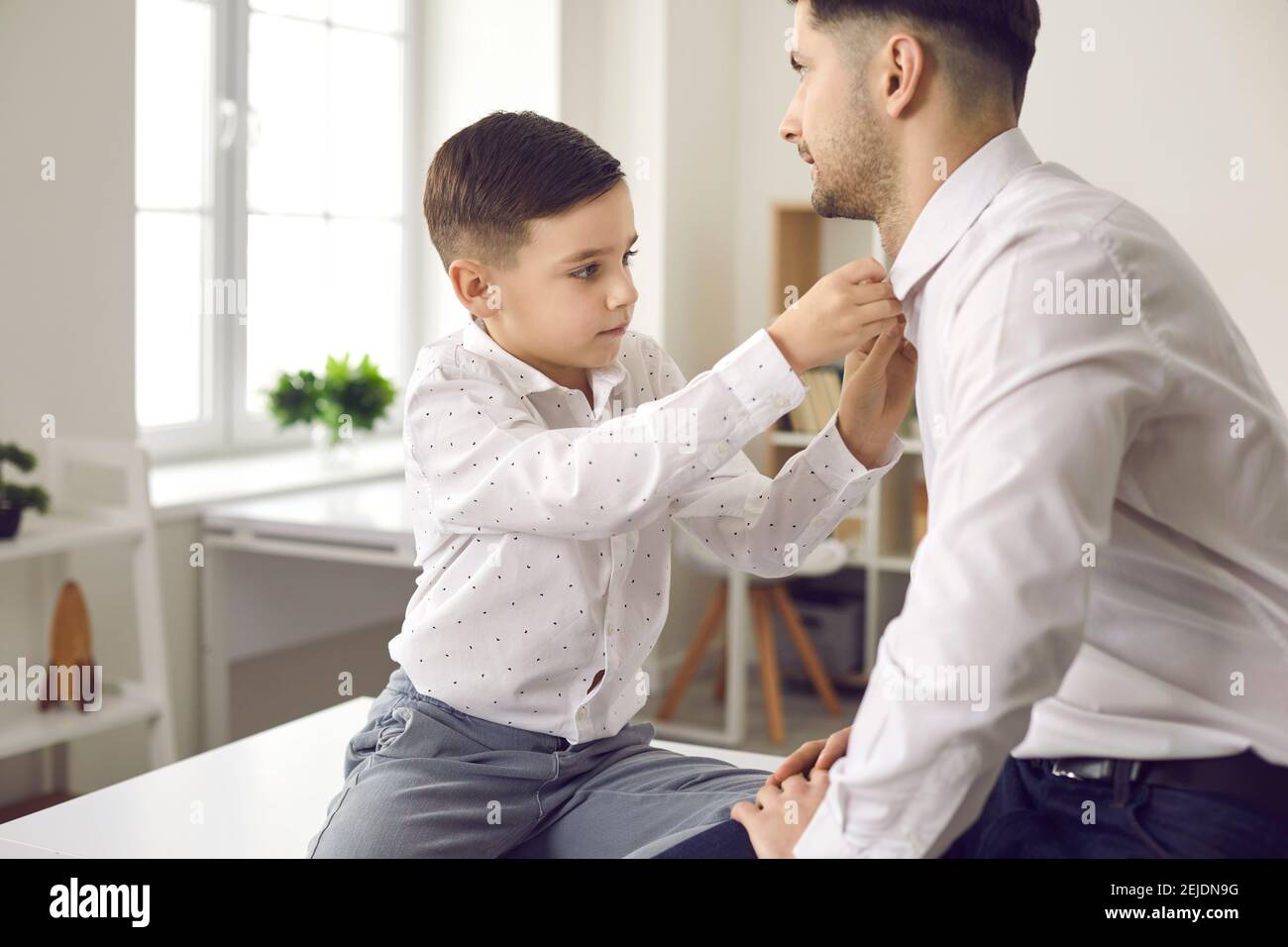 Father and little son dressing up and putting on white shirts for ...