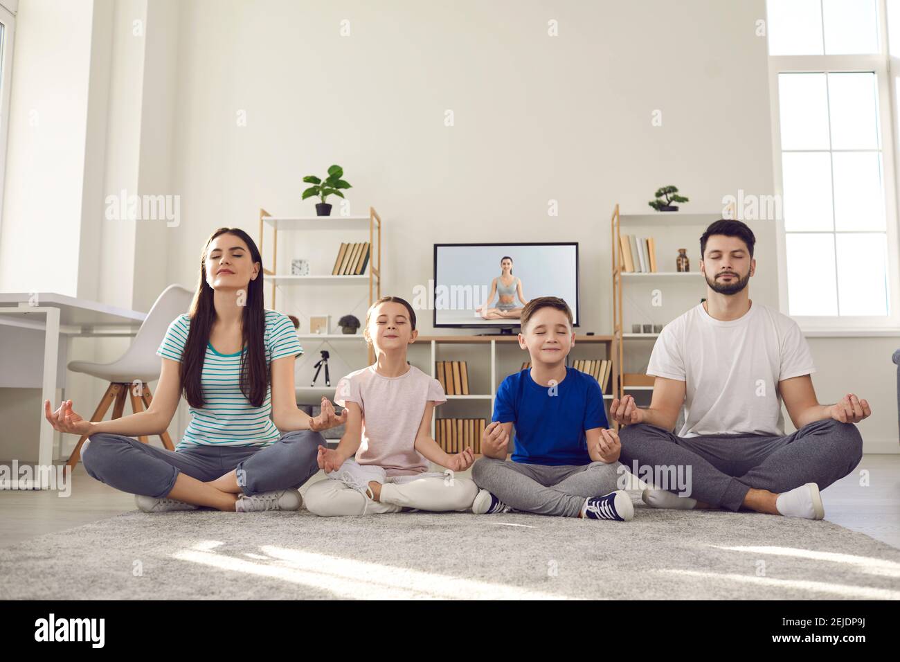 Happy young family with children practicing meditation and reaching zen ...