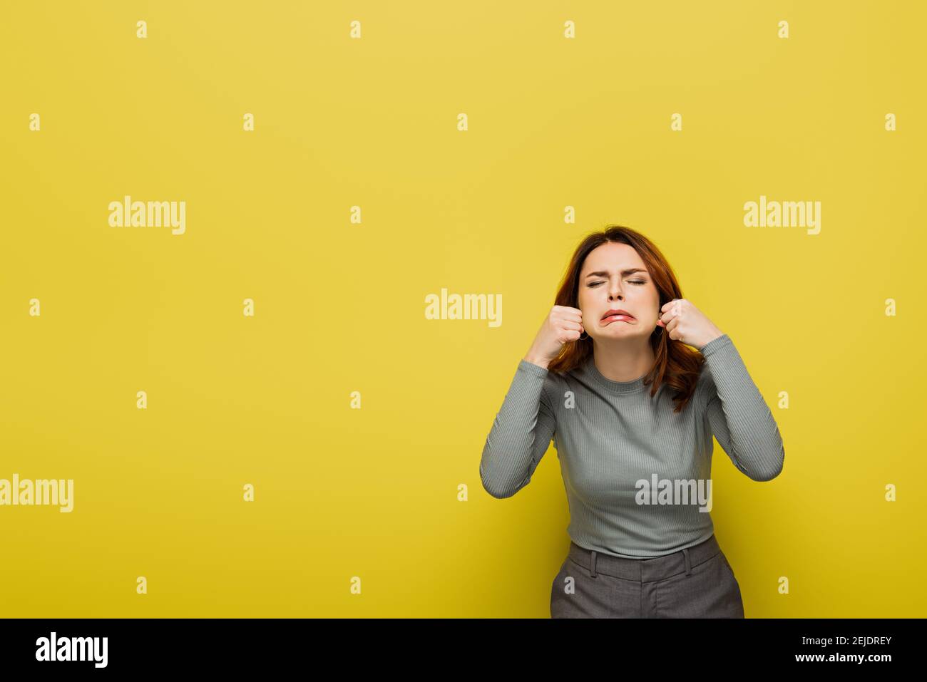 frustrated woman with clenched fists crying isolated on yellow Stock ...
