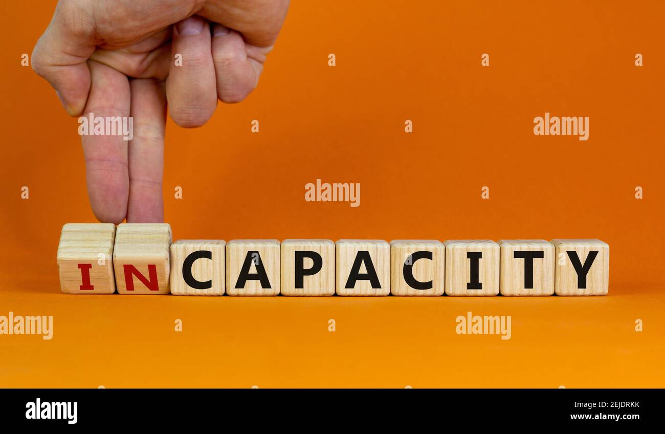 Capacity or incapacity symbol. Businessman turns wooden cubes and ...