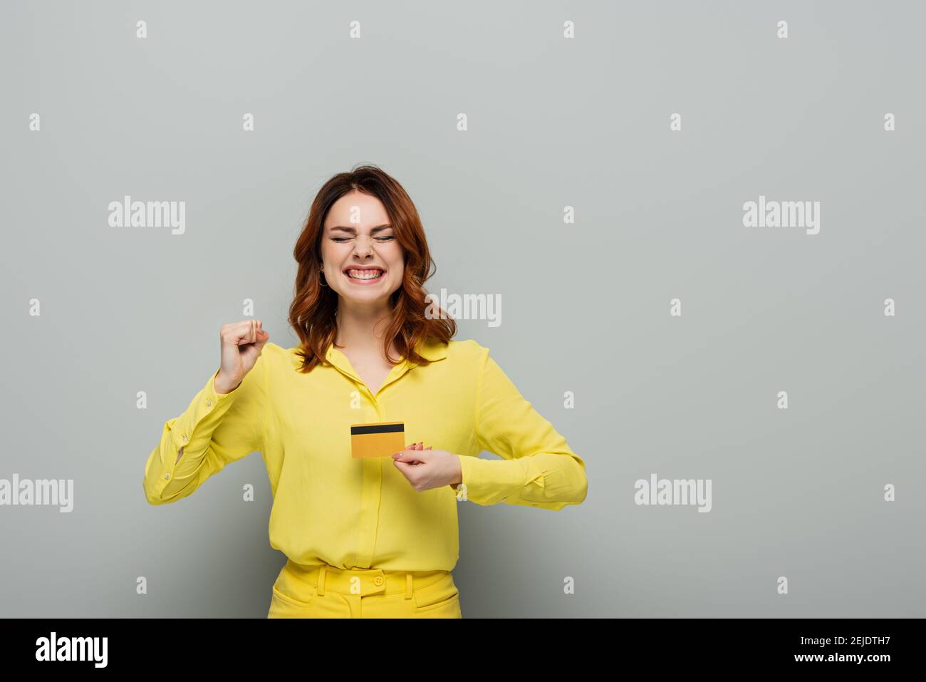 excited woman with closed eyes showing yeah gesture while holding ...