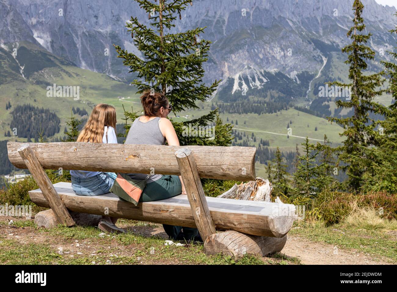 Mother and daughter sitting on a bench enjoying the view of the ...