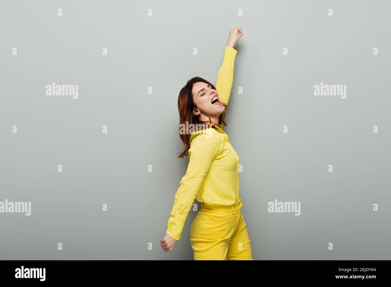 excited woman showing yeah gesture and shouting while standing with ...