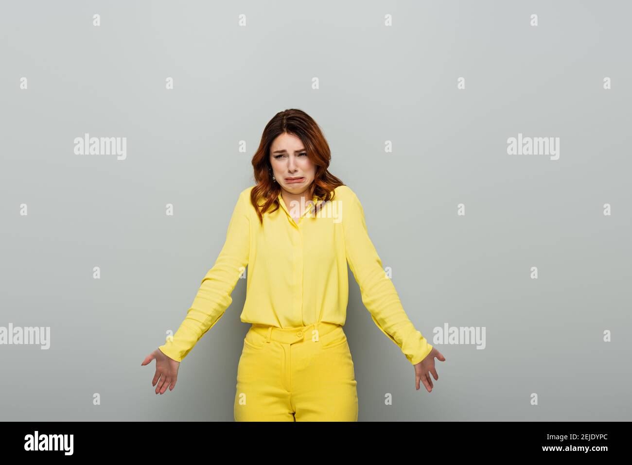 frustrated woman showing shrug gesture while grimacing on grey Stock ...