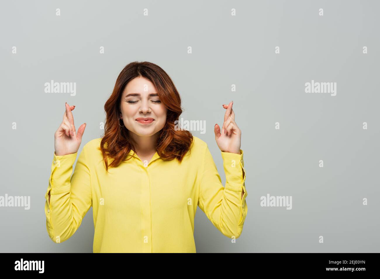 Positive Woman Holding Crossed Fingers While Standing With Closed Eyes