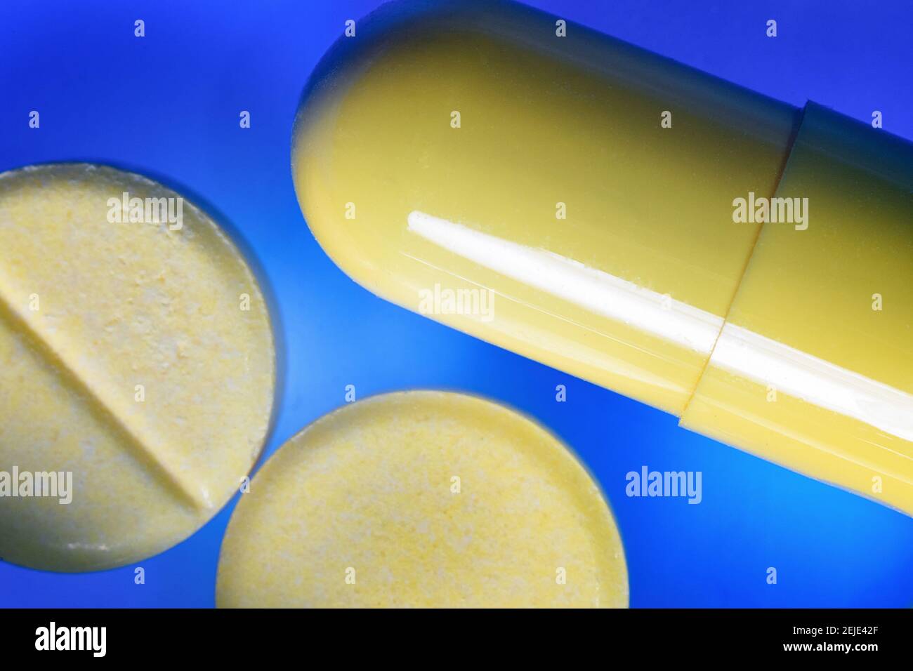 yellow round pill and capsules close-up. macro. blue background Stock ...