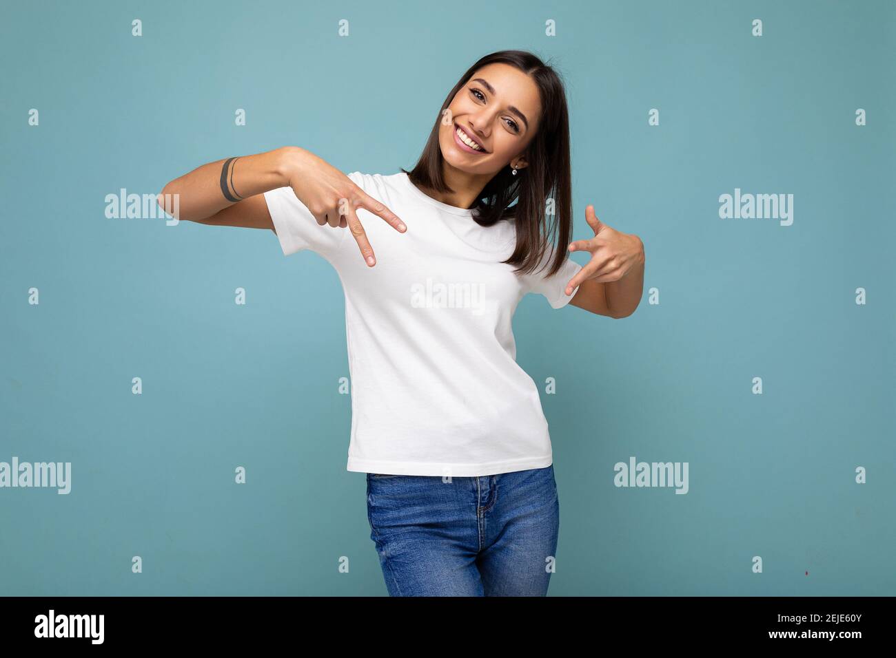 Photo of attractive positive smiling young woman pointing fingers down ...
