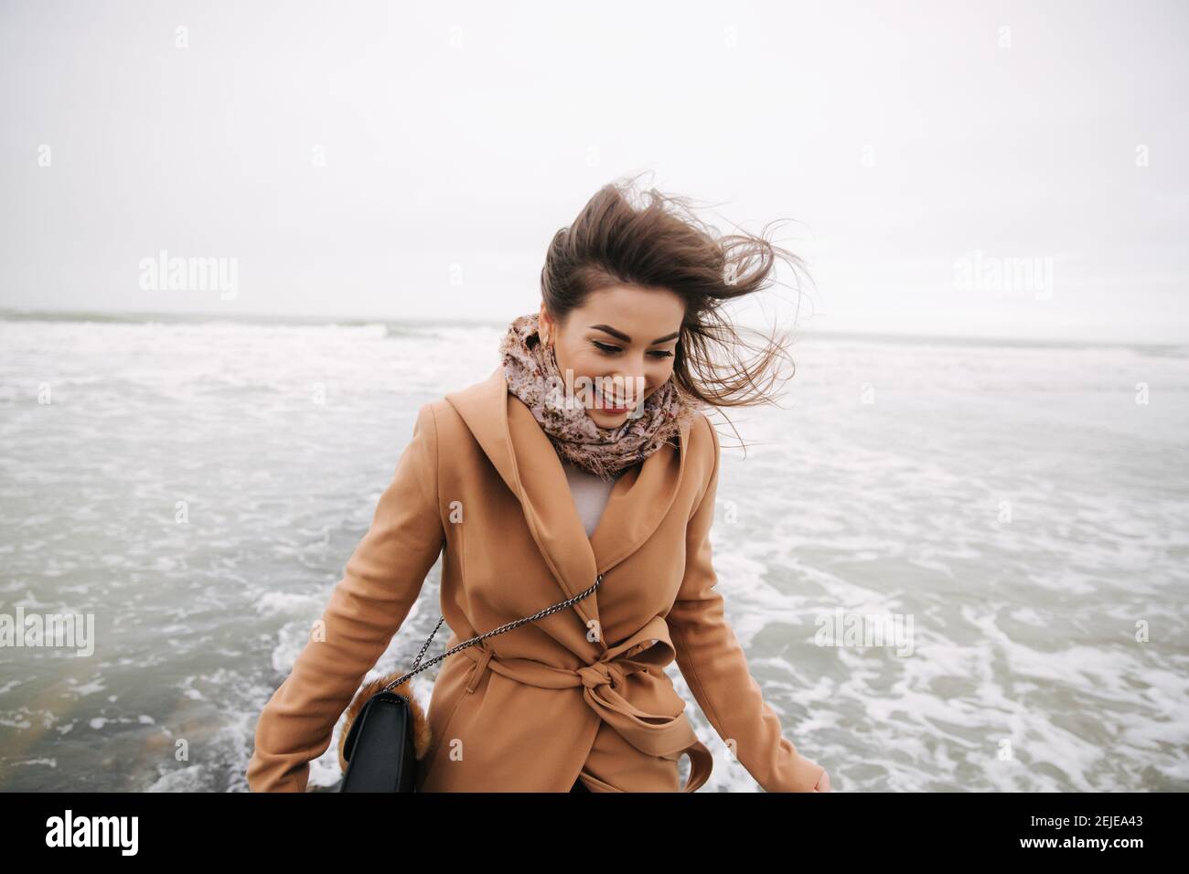 Woman running away from the waves of North Sea. Female afraid to be wet ...