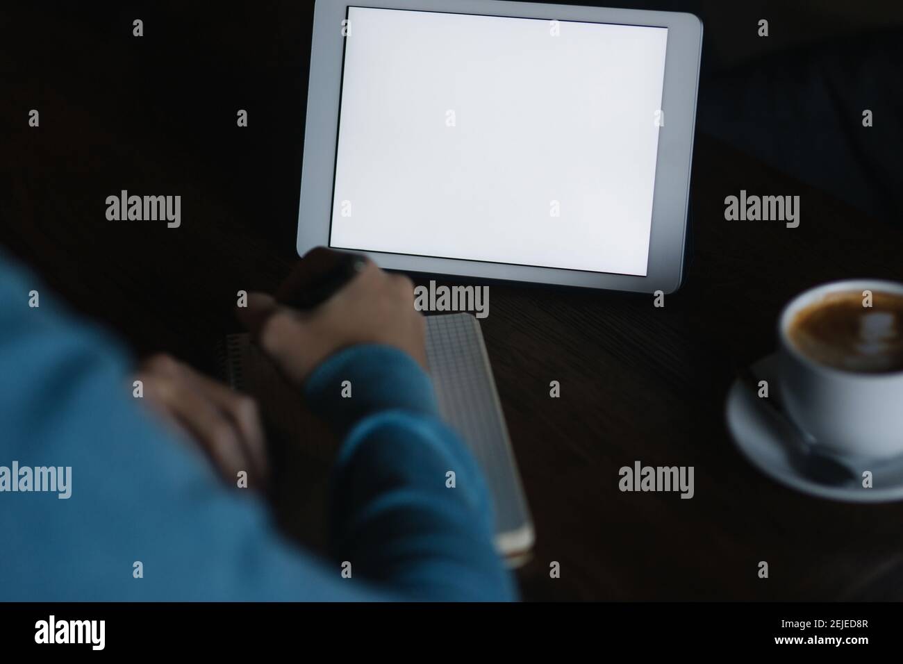 Man is sitting in a cafe and uses a tablet and write down something in ...