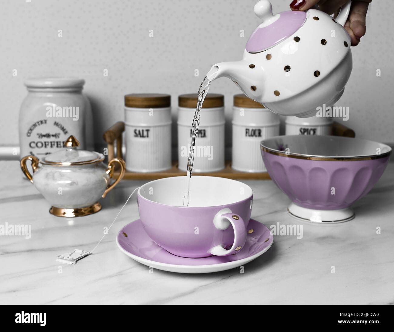 Closeup shot of water being poured into a purple teacup set in the ...