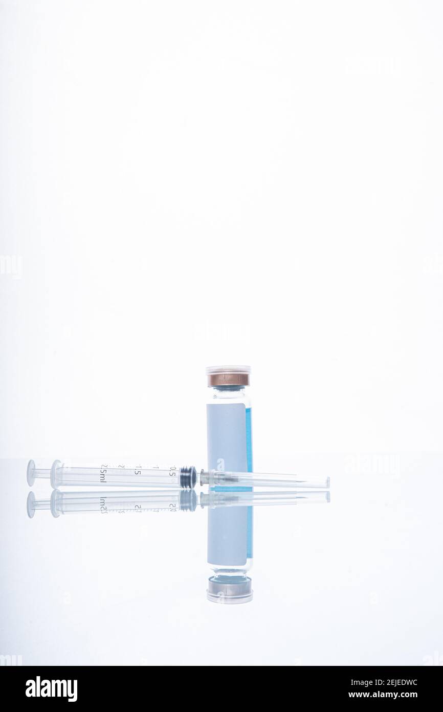 Vertical shot of a medical vial with a syringe on a white background ...