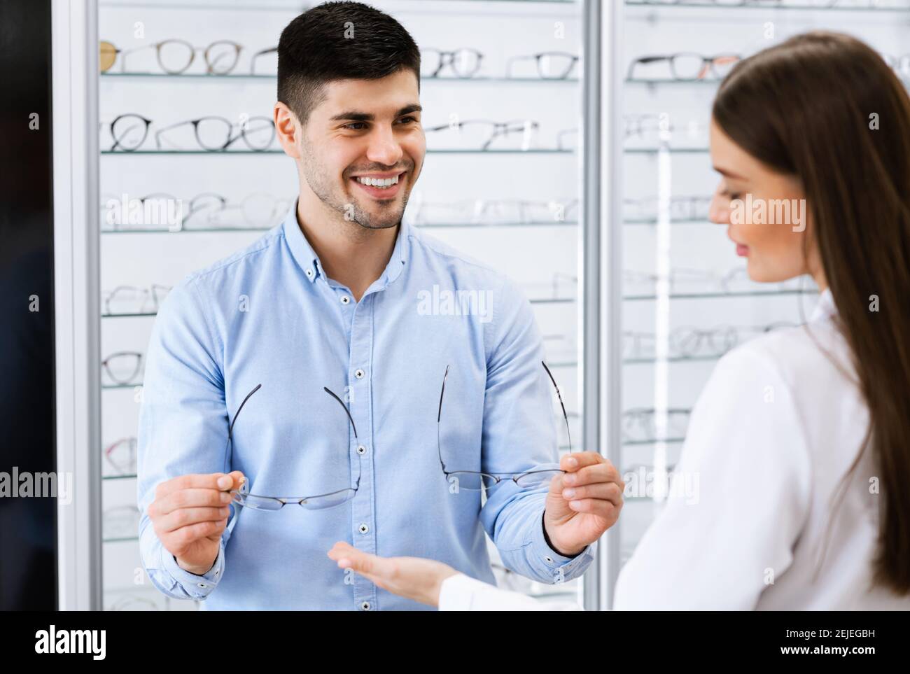 Female optometrist helping guy to choose new correction glasses Stock ...