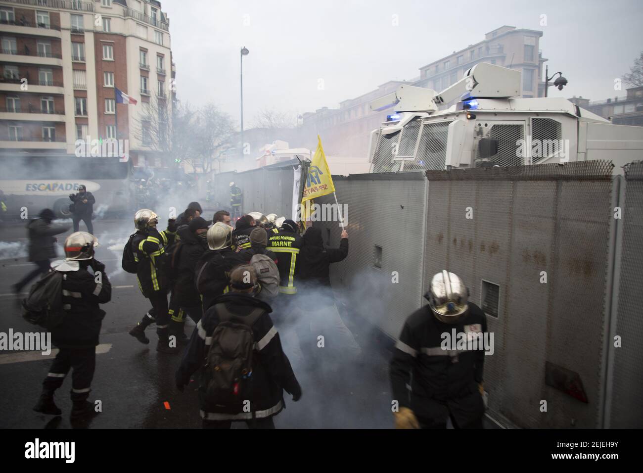 Paris firefighters attempt to open a police barricade as officers spray ...