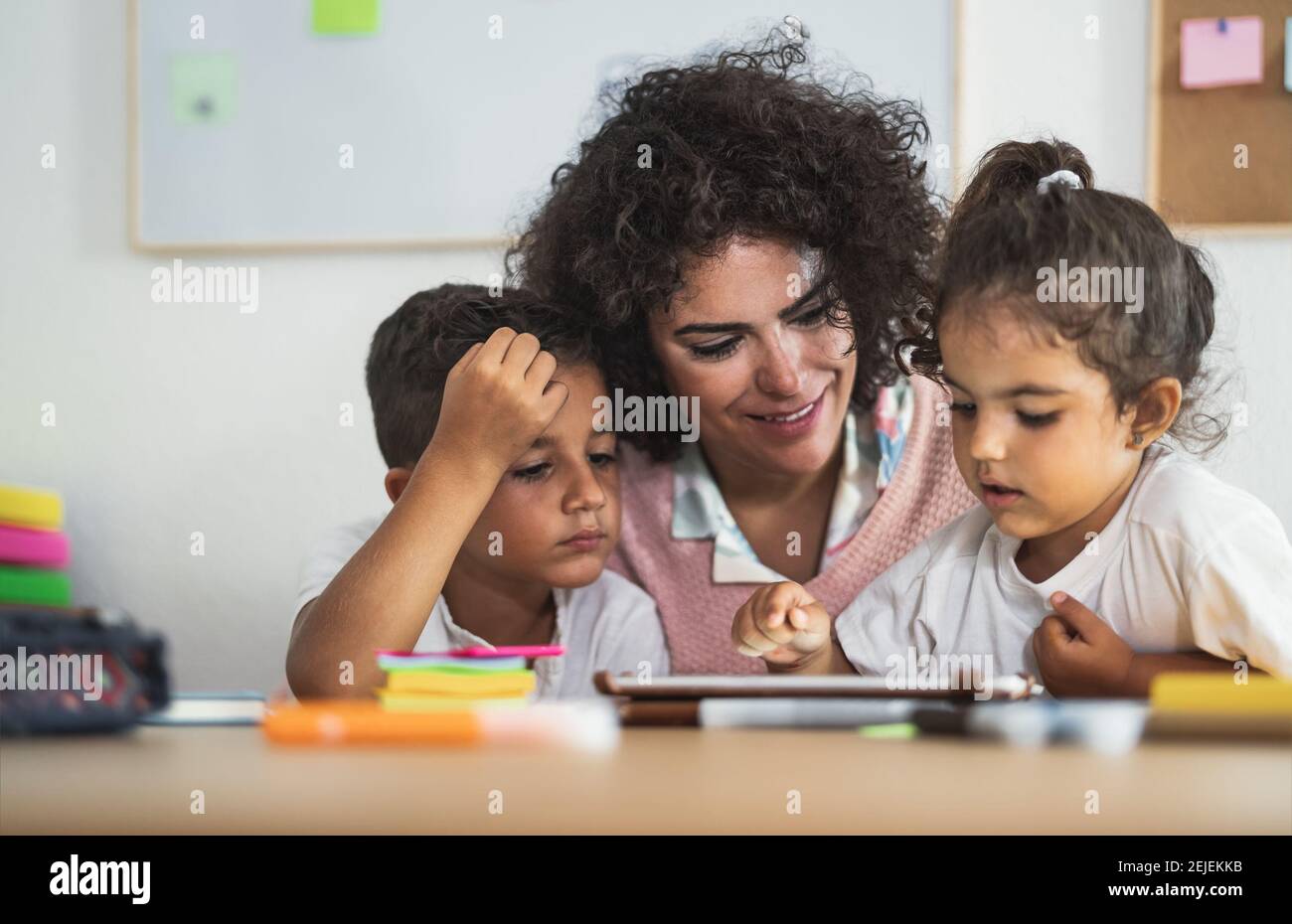 Teacher with children using digital tablet in preschool classroom ...