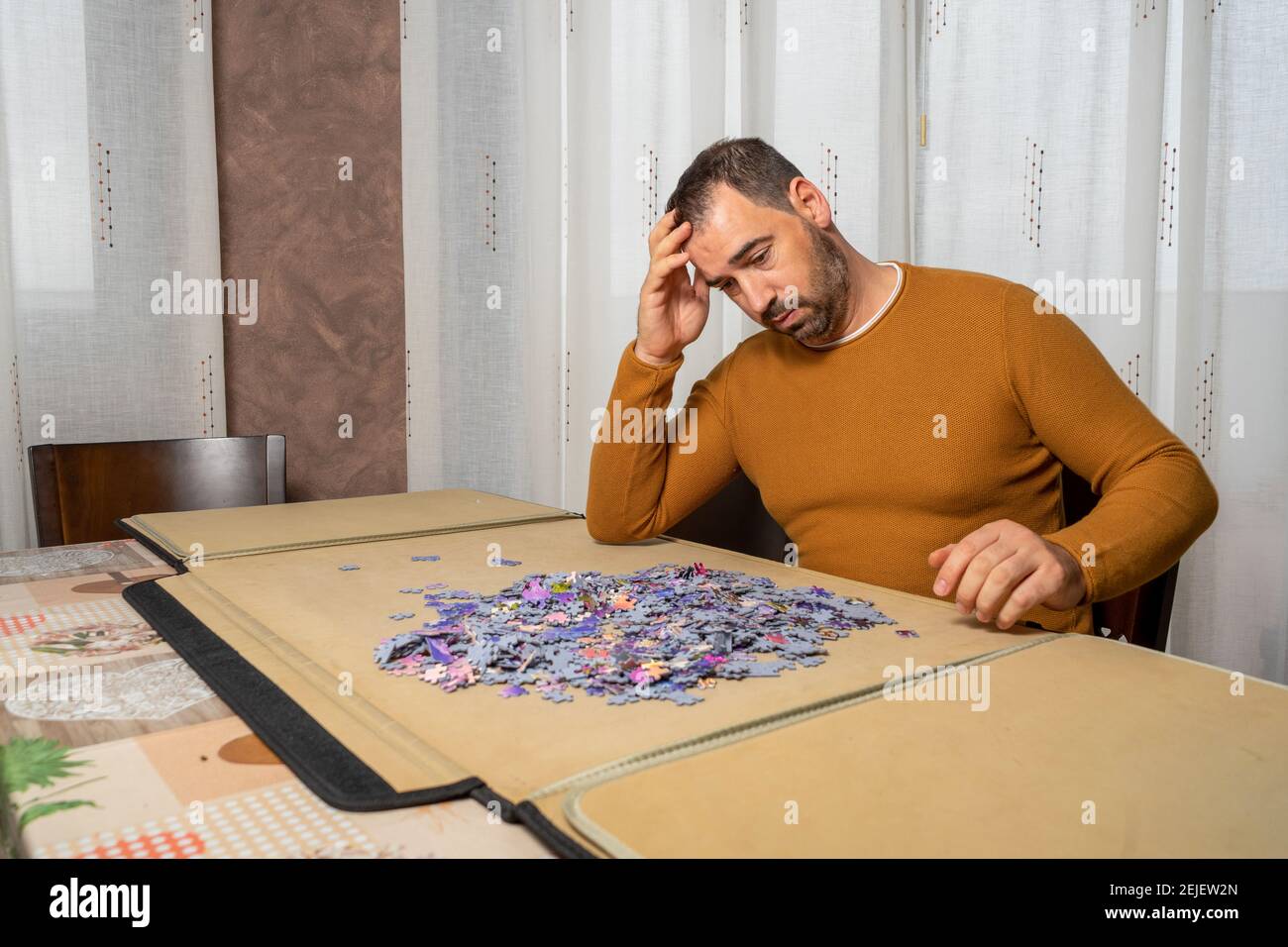 Handsome bearded man in an orange sweater with his hand on his head ...