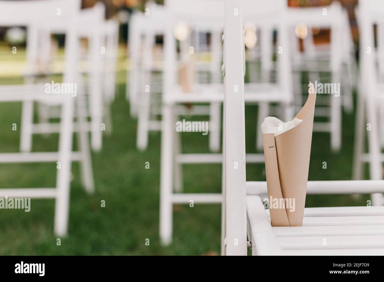 White folding chairs with paper packages with petals on green lawn for ...