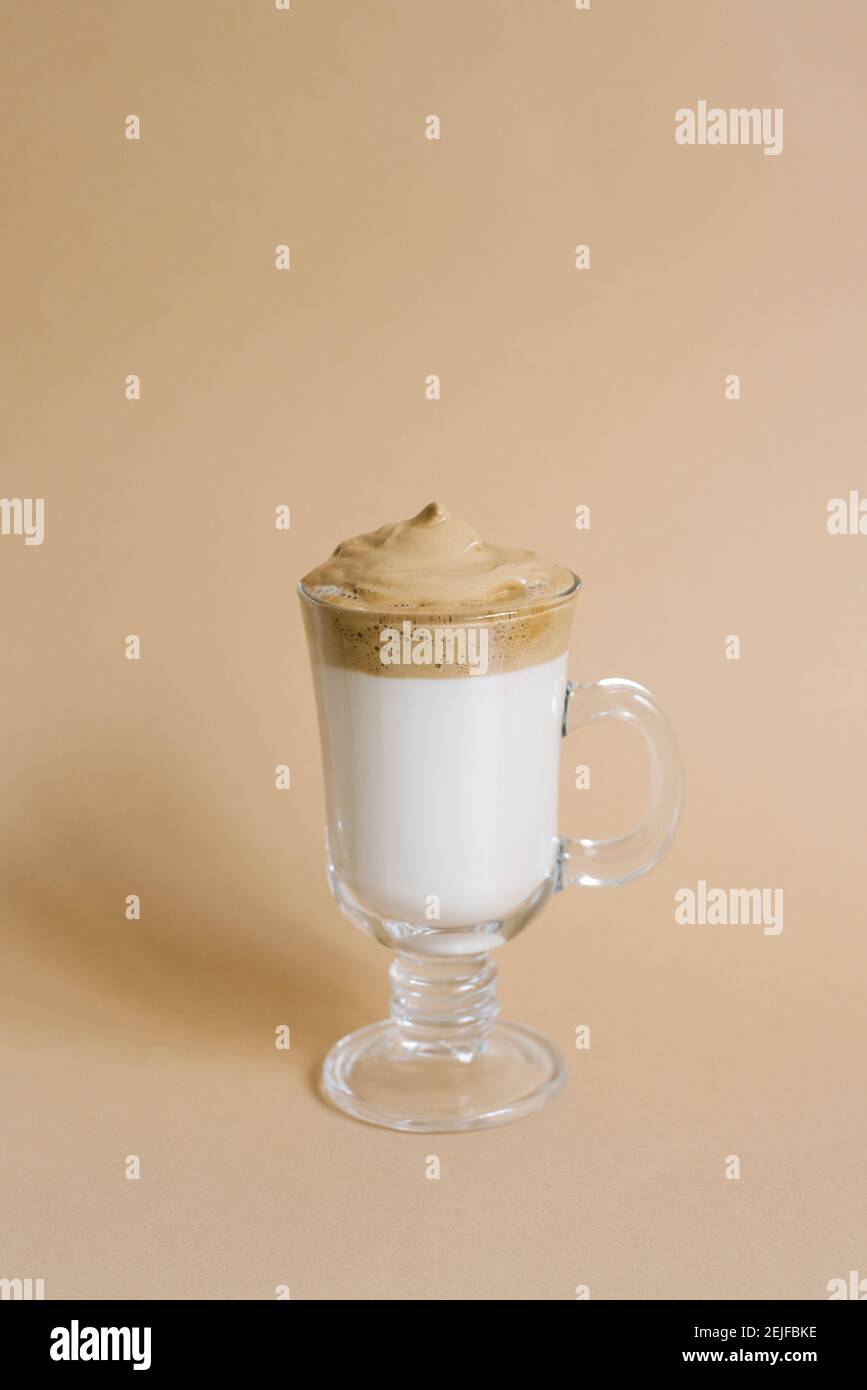 Beautiful dalgon drink coffee with foam in a transparent mug on a beige ...