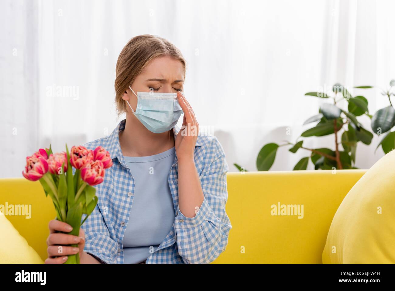 Young woman in medical mask holding tulips during allergy reaction ...