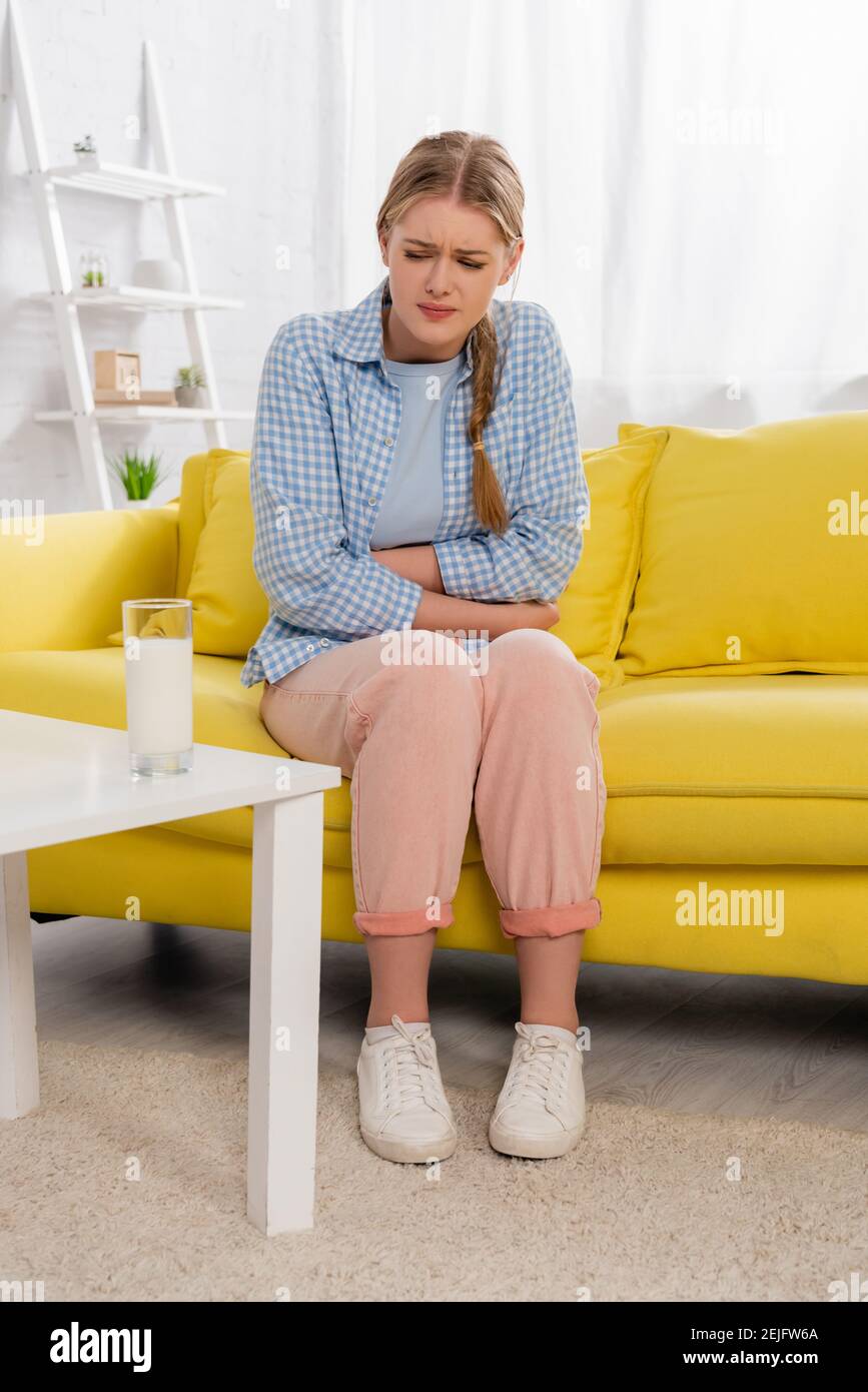 Sad woman with lactose intolerance looking at glass of milk Stock Photo ...
