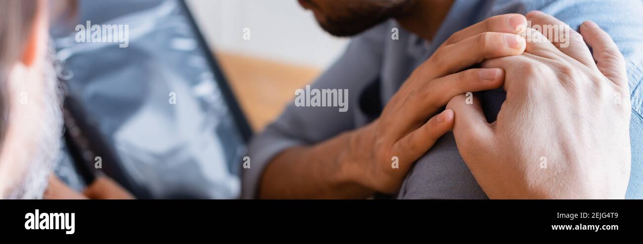 cropped view of father touching shoulder of son holding photo album ...