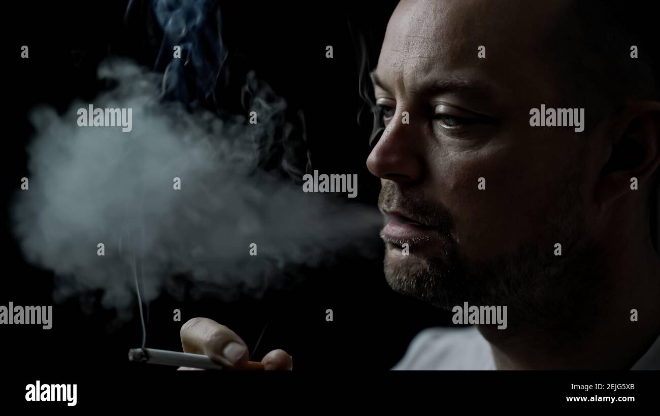 Man smoking a cigarette and blowing smoke out of his mouth Stock Photo ...
