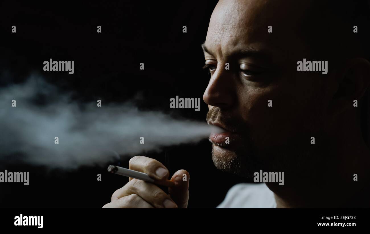 Man smoking a cigarette and blowing smoke out of his mouth Stock Photo ...