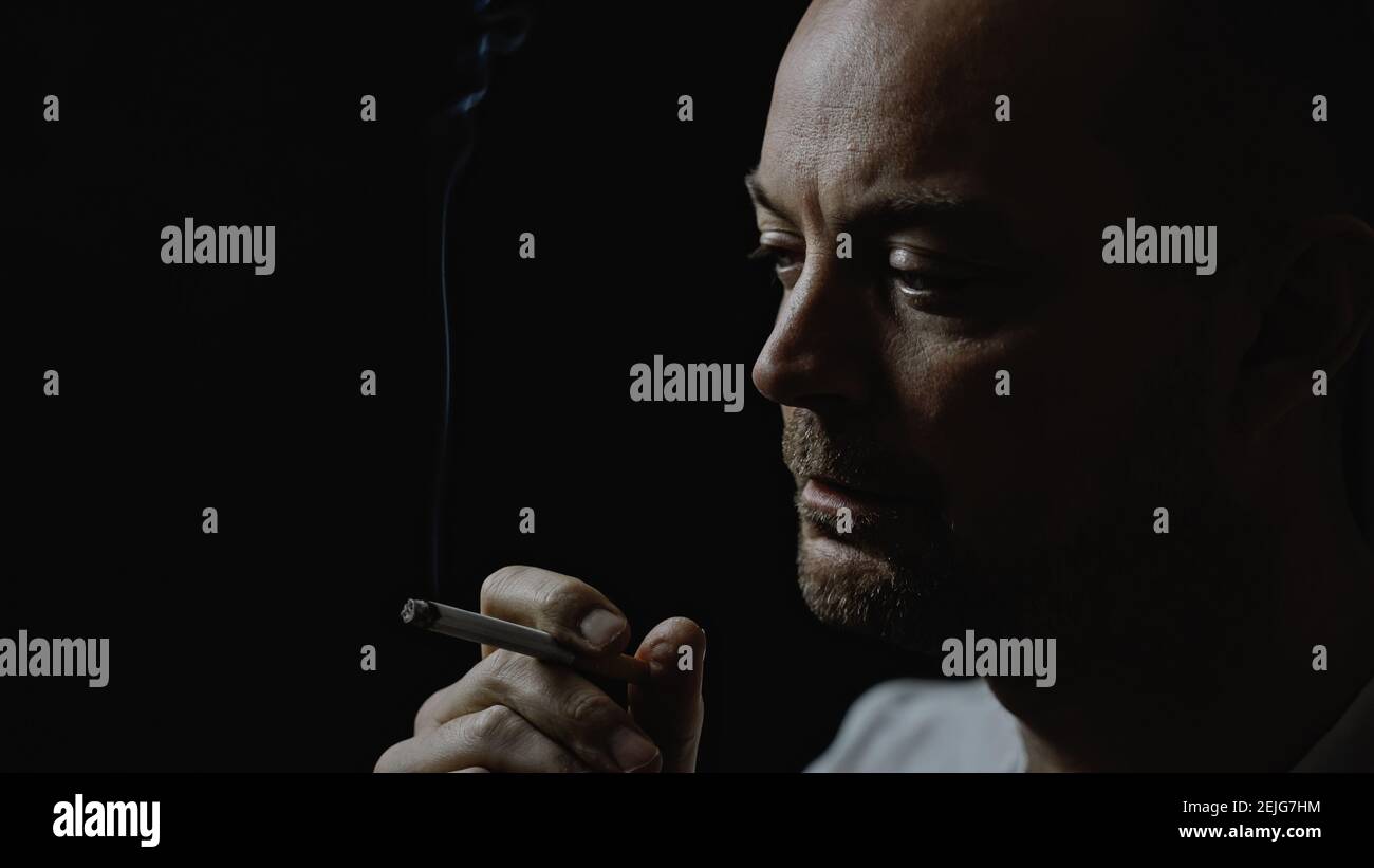 Close up of a young man smoking a cigarette looking thoughtful and ...