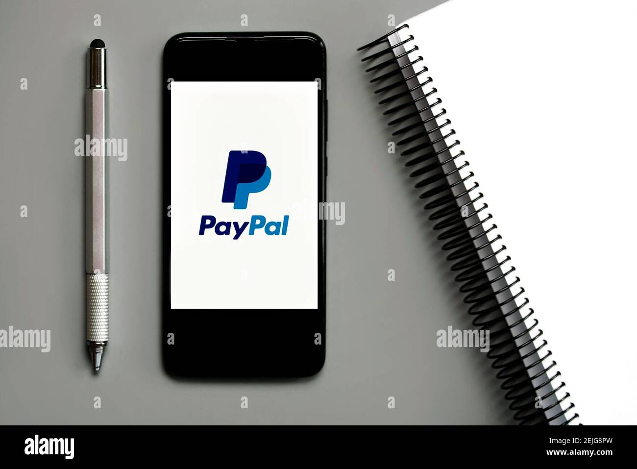 Paypal logo on black screen of smartphone with gray pen on a gray ...