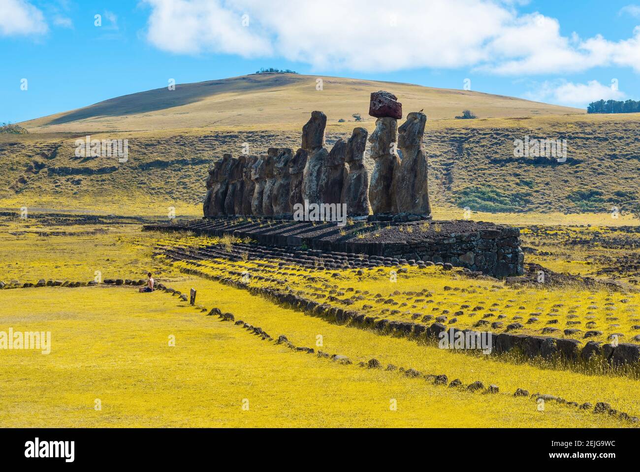 Young woman tourist sitting in front of the Moai statues of Ahu ...