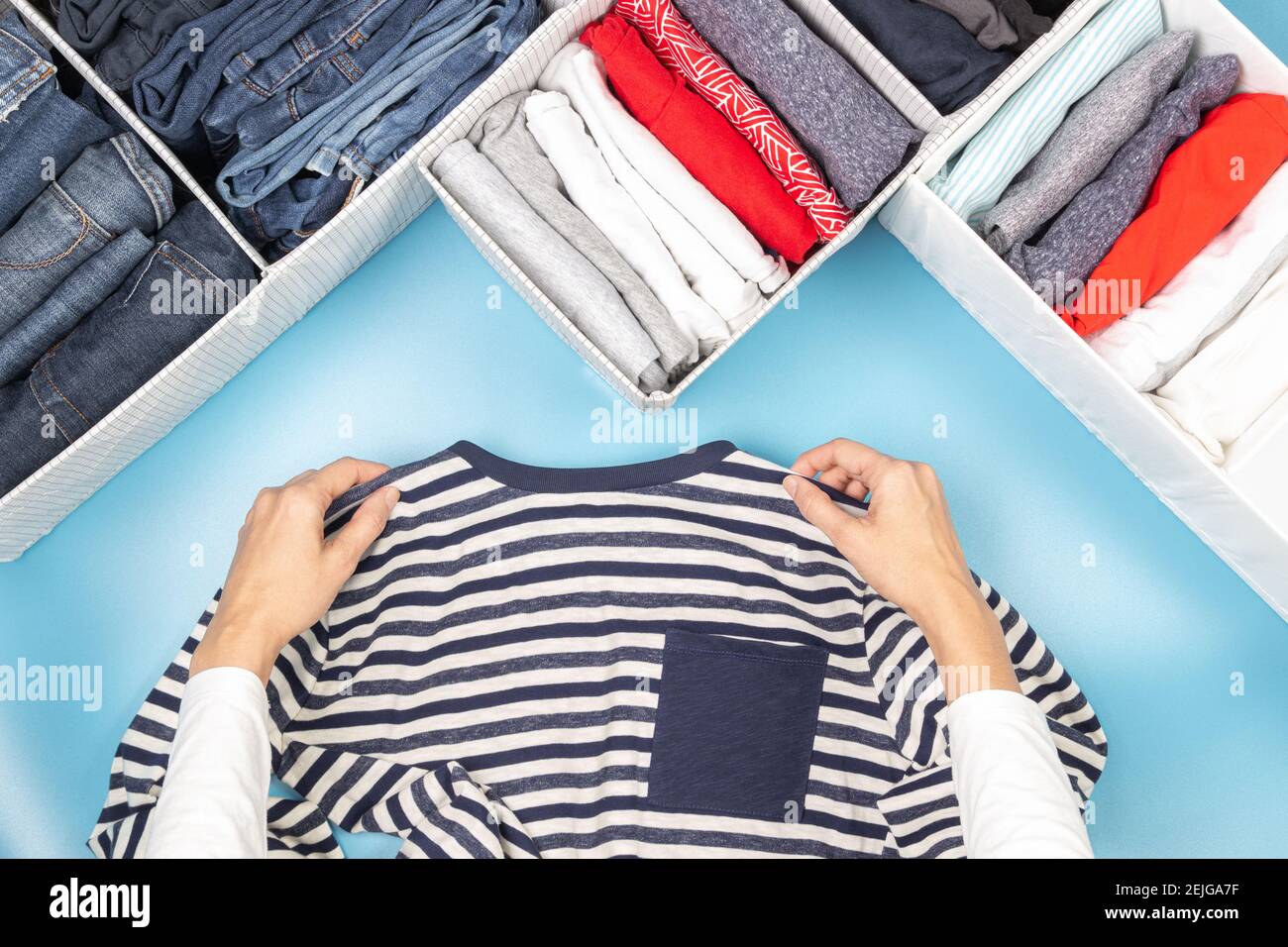 Woman hands folds and puts clothes to baskets. Vertical clothing ...