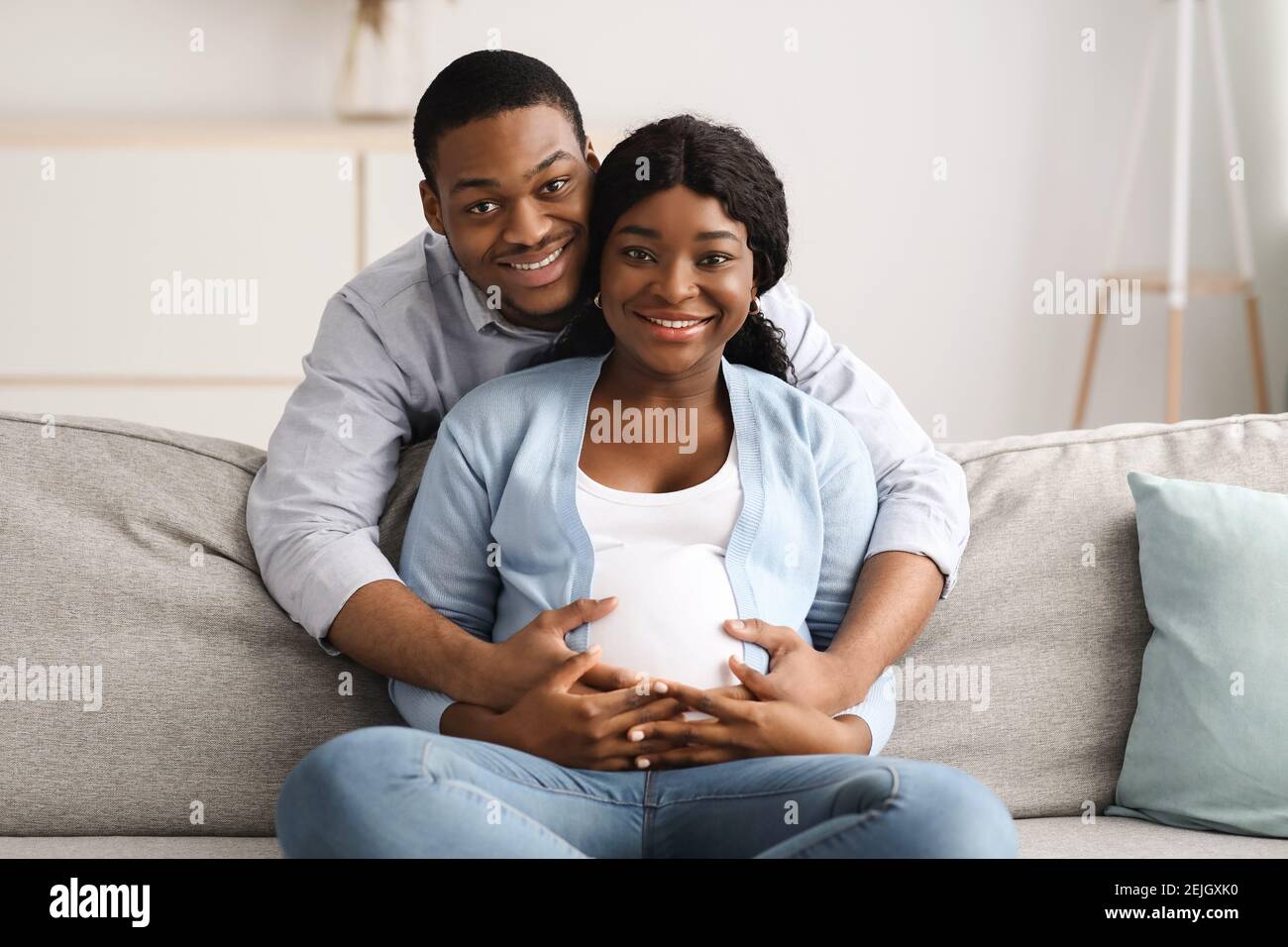 Happy expecting couple cuddling while spending time at home Stock Photo ...